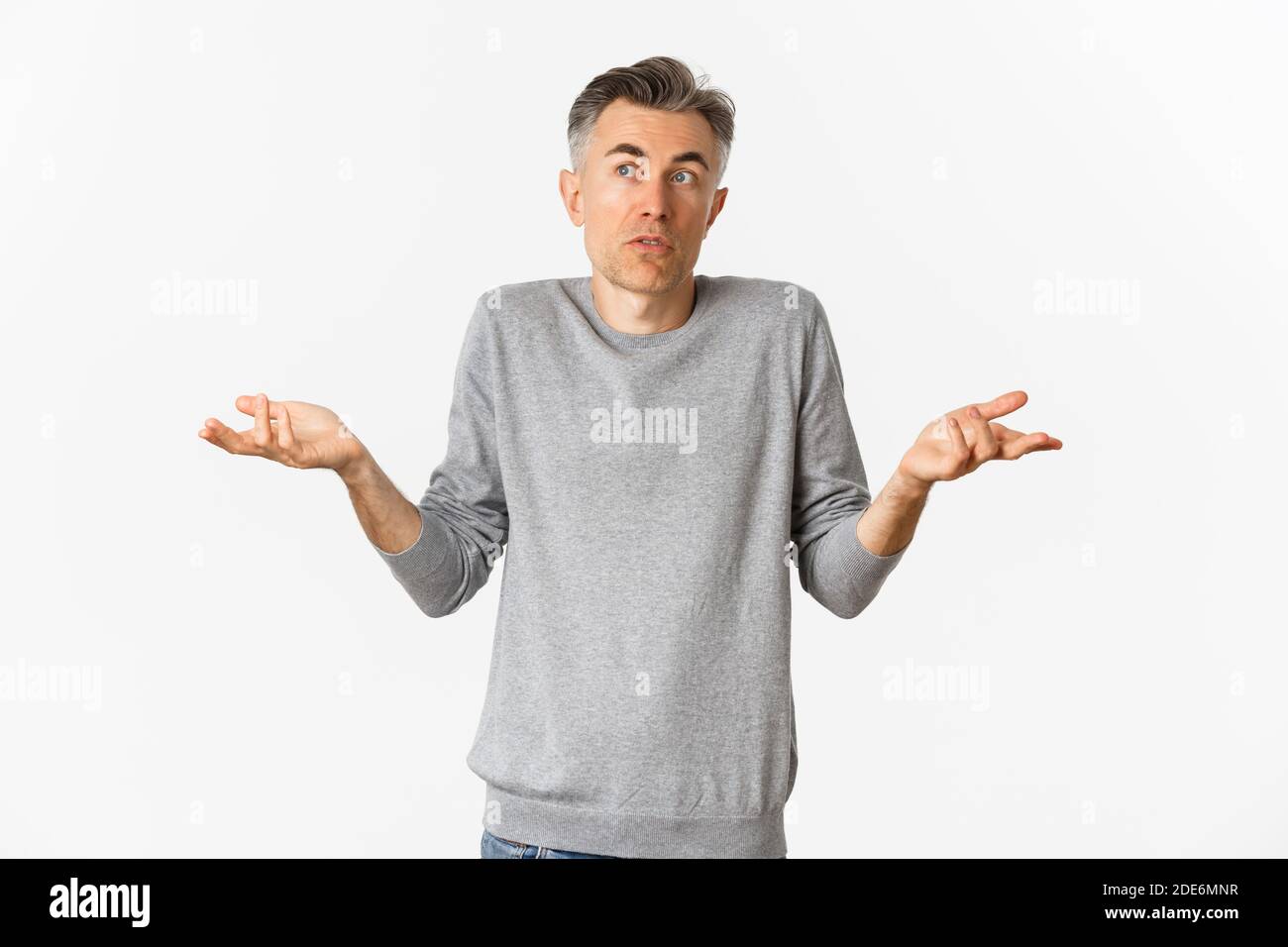 Image of confused middle-aged man with grey hair, shrugging and looking ...