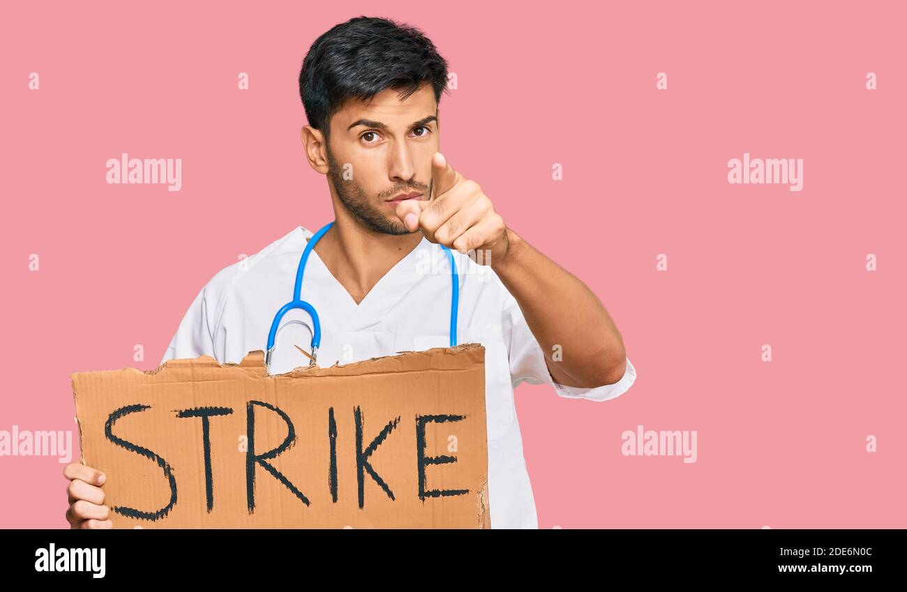 Young handsome man wearing doctor uniform holding strike banner ...