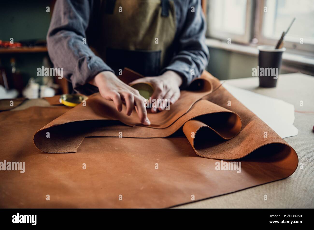 A young shoemaker starts manufacturing shoes, lays out a roll of ...