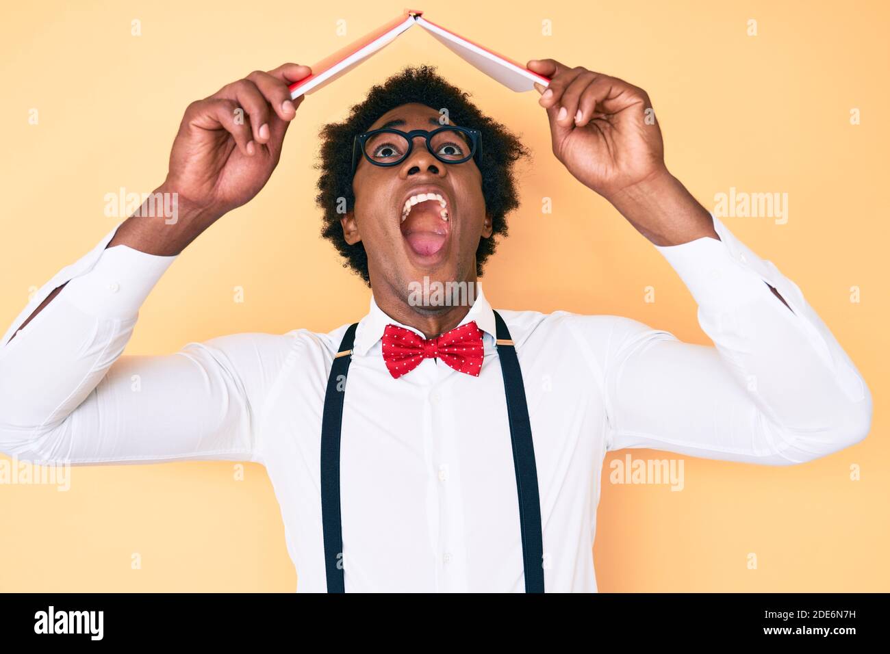 Handsome african american nerd man with afro hair holding book over ...