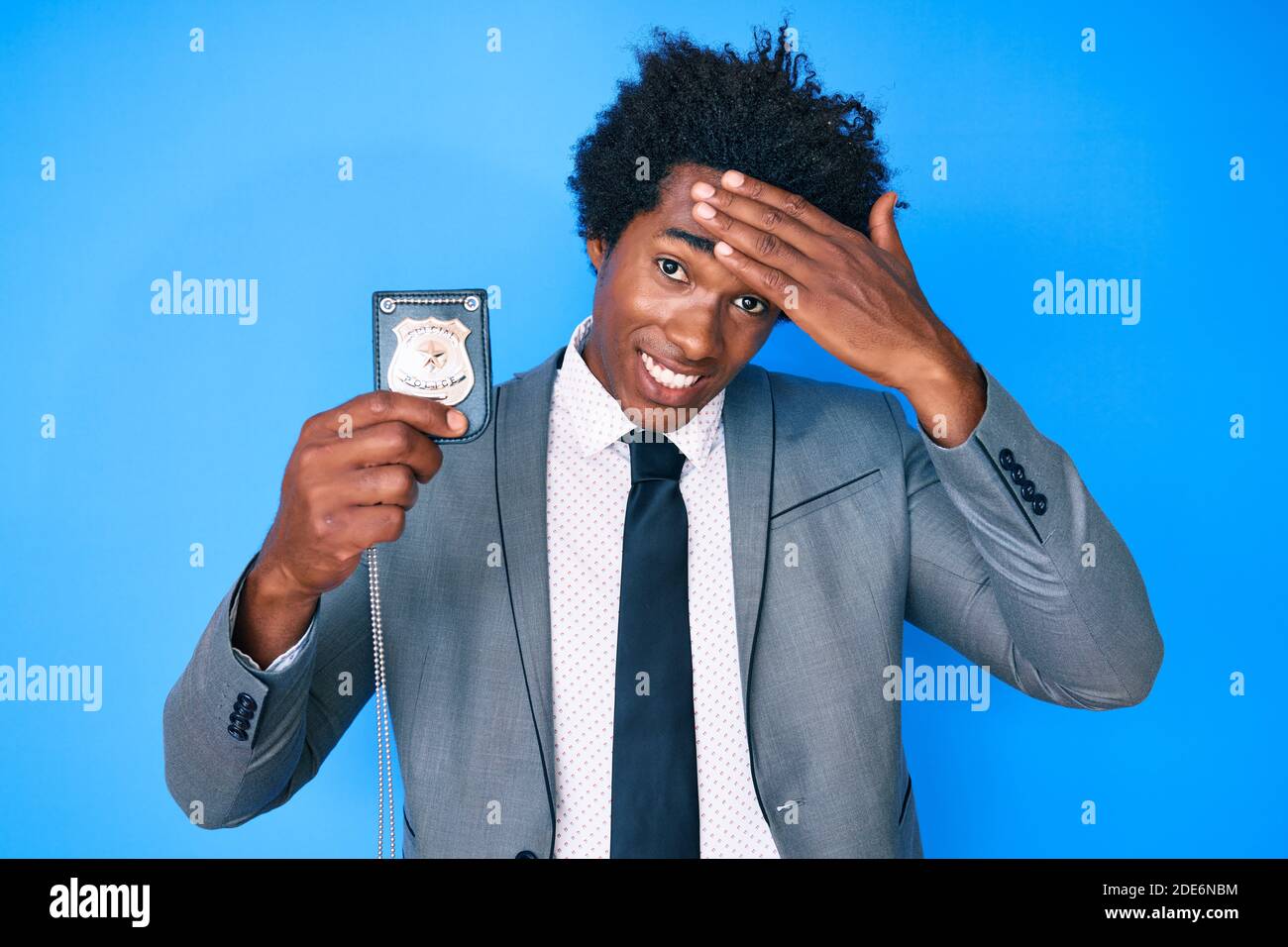 Handsome african american man with afro hair holding detective badge ...