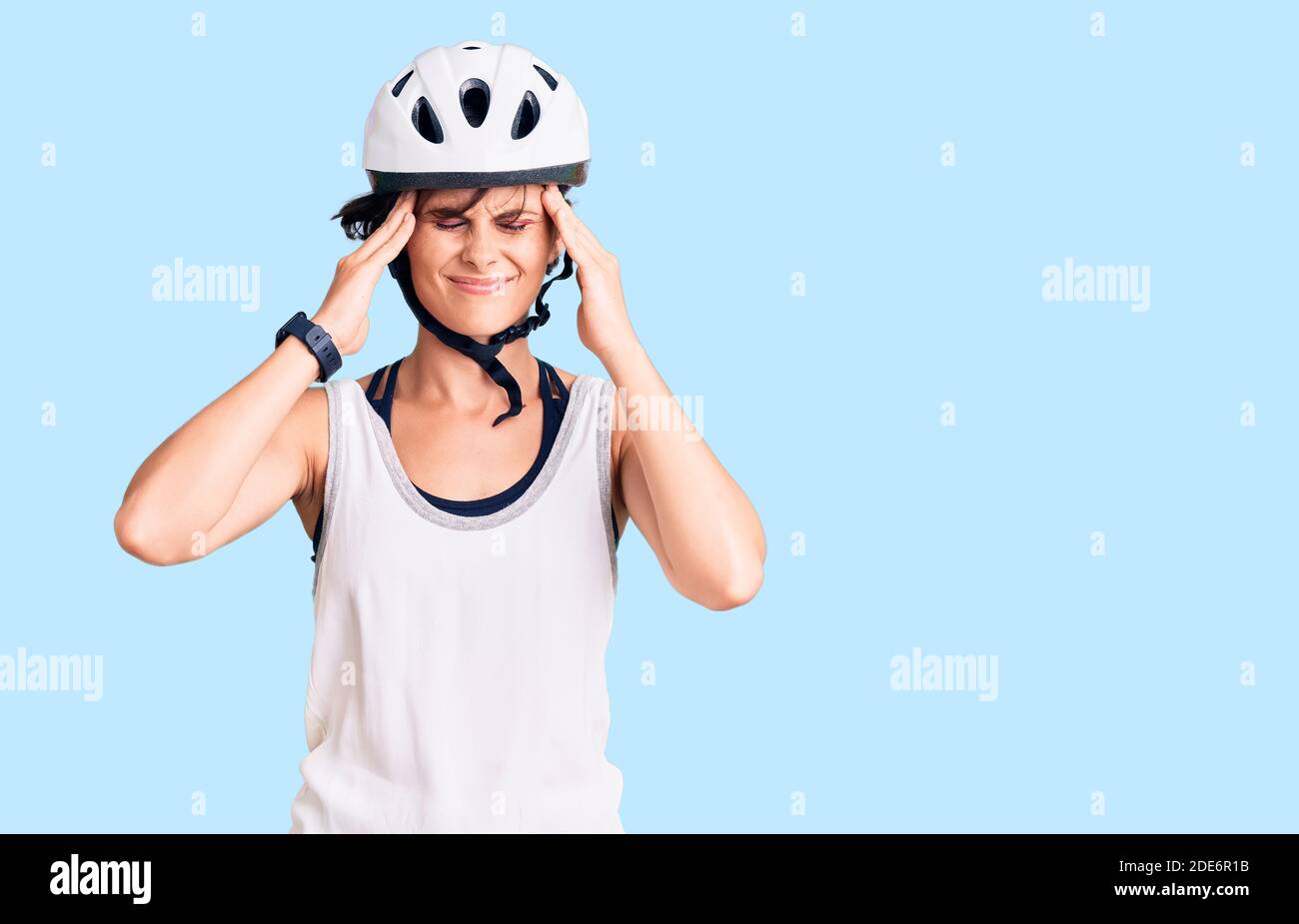 Beautiful young woman with short hair wearing bike helmet suffering ...