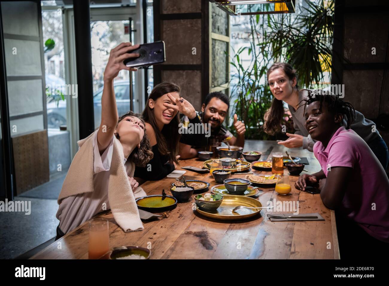A multicaltural group of students taking photos of themselves, making ...