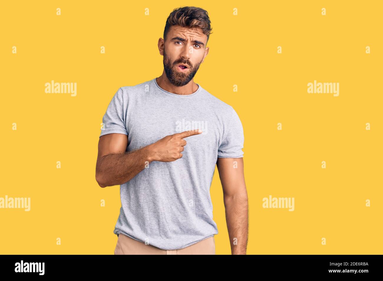 Young hispanic man wearing casual clothes surprised pointing with ...