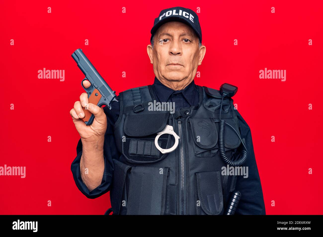 Senior man with grey hair wearing police uniform holding gun thinking ...