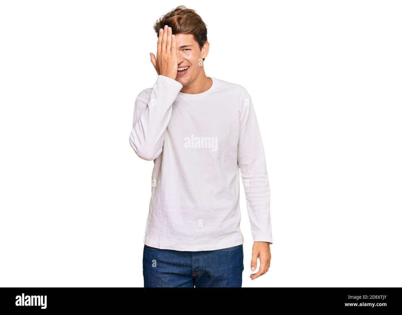 Handsome caucasian man wearing casual white sweater covering one eye ...