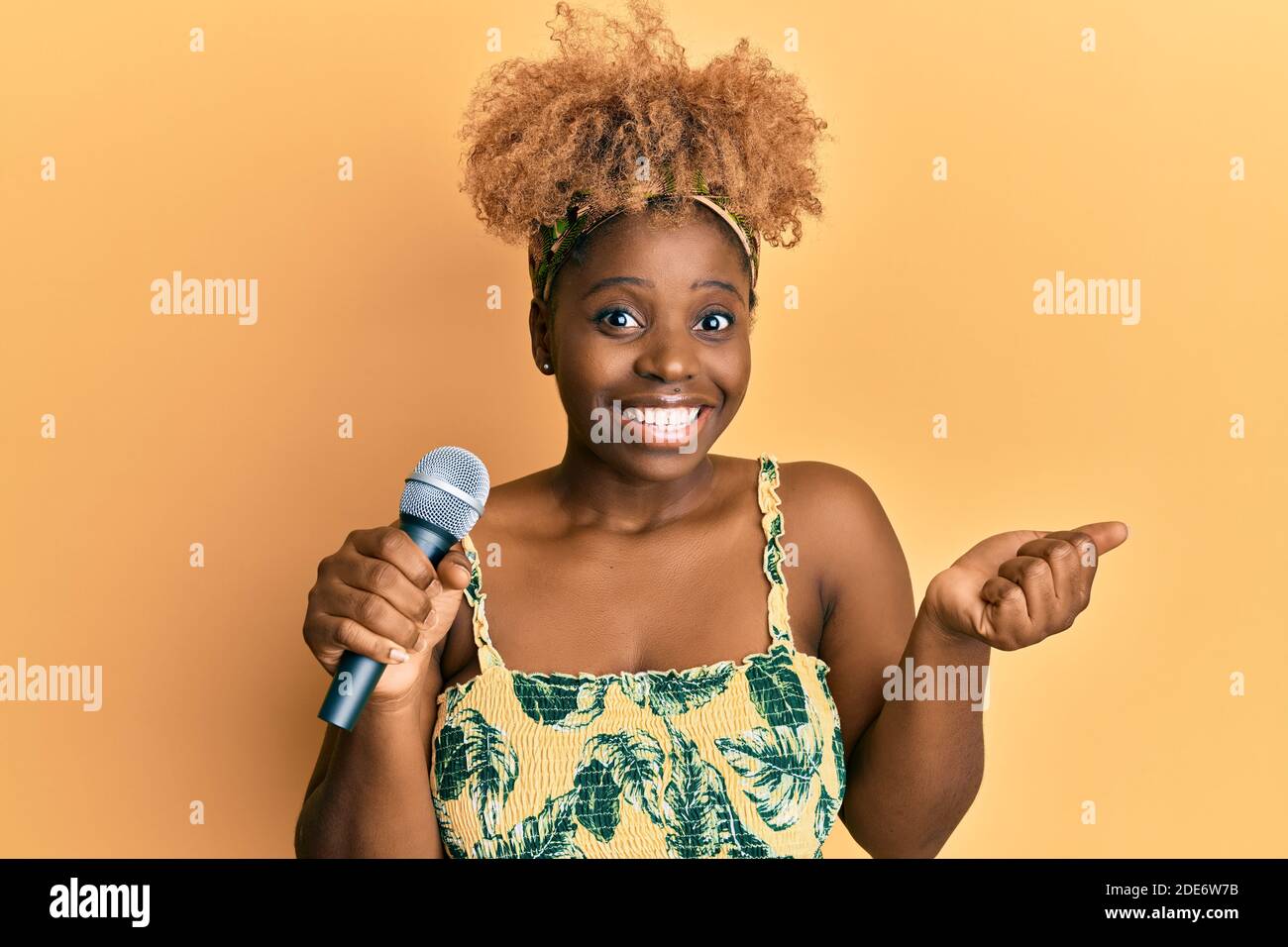 Young african woman with afro hair singing song using microphone ...