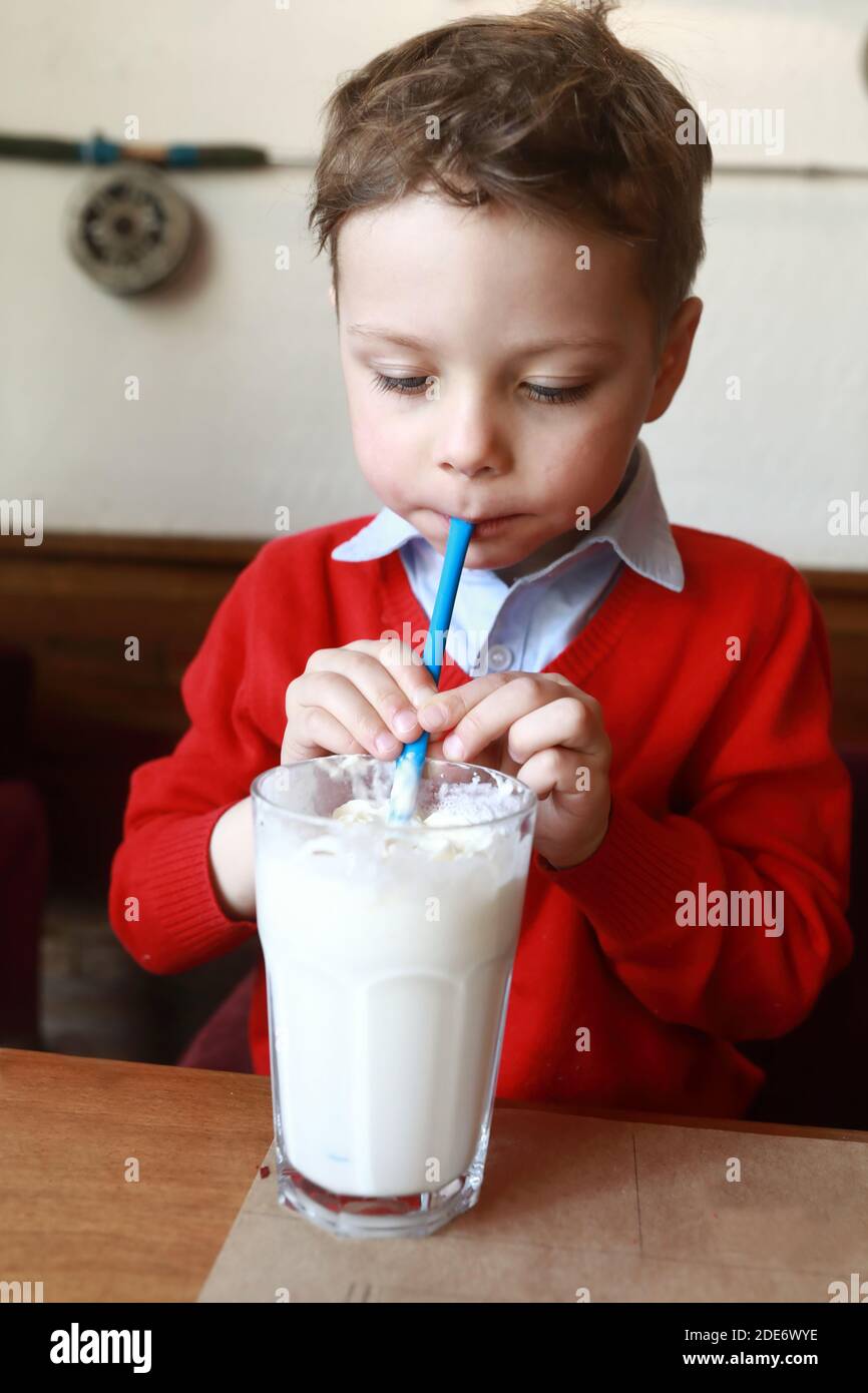 Boy drinking milkshake at table in restaurant Stock Photo - Alamy