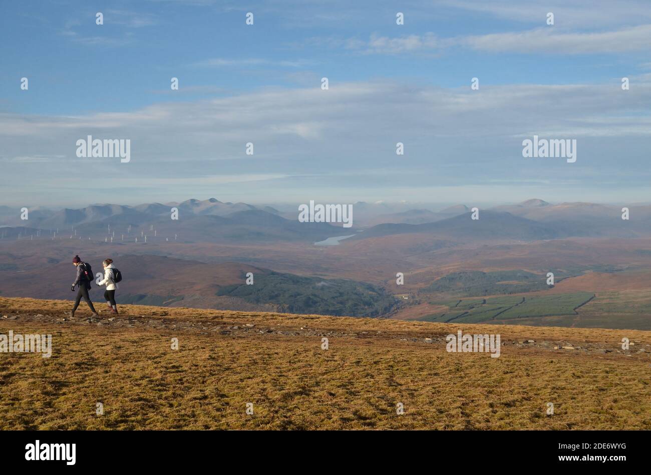 Two people walking along a mountain ridge at Ben Wyvis, in the Scottish ...