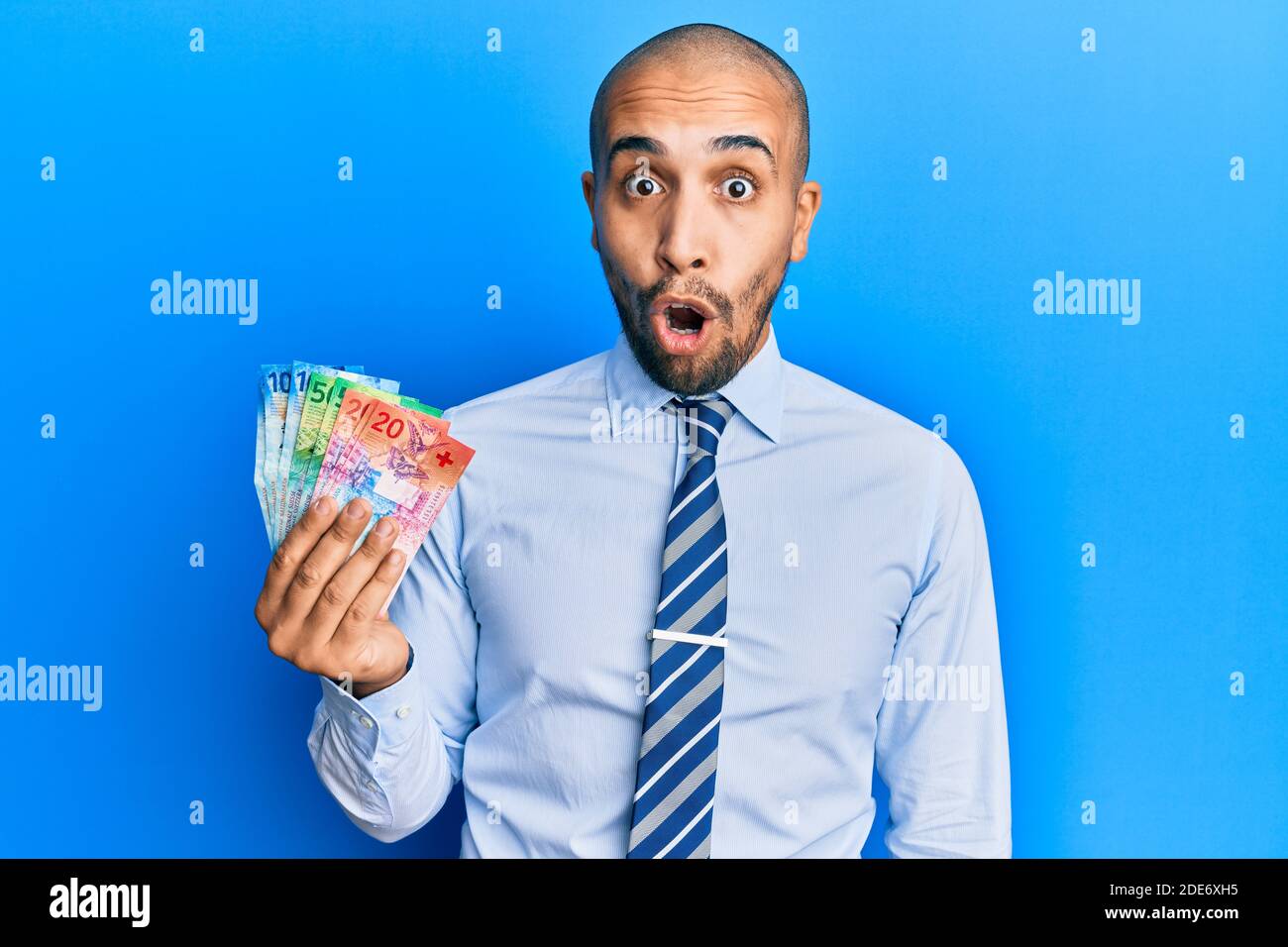 Hispanic adult business man holding swiss franc banknotes scared and ...