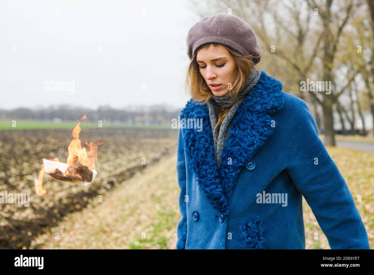Beautiful decisive girl in blue coat stay at open field with flying ...
