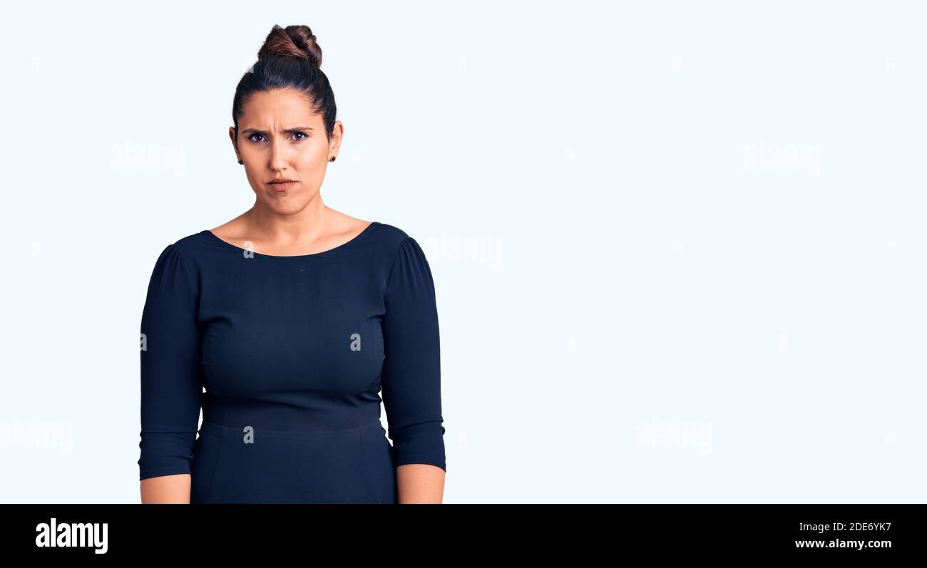 Young beautiful brunette woman wearing casual dress skeptic and nervous ...