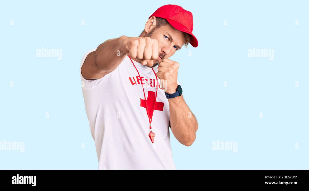 Young caucasian man wearing lifeguard t shirt holding whistle punching ...