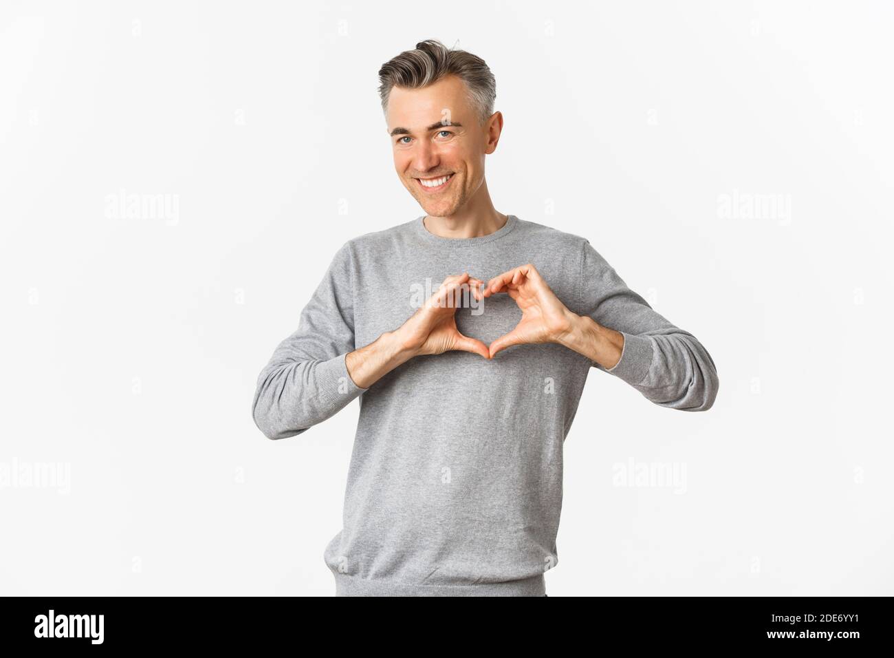 Portrait of cheeky middle-aged man in grey sweater, smiling and showing ...