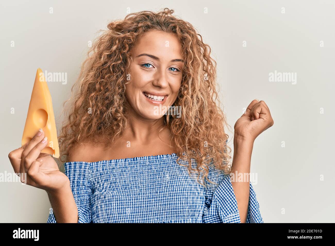 Beautiful caucasian teenager girl holding a piece of emmental cheese ...