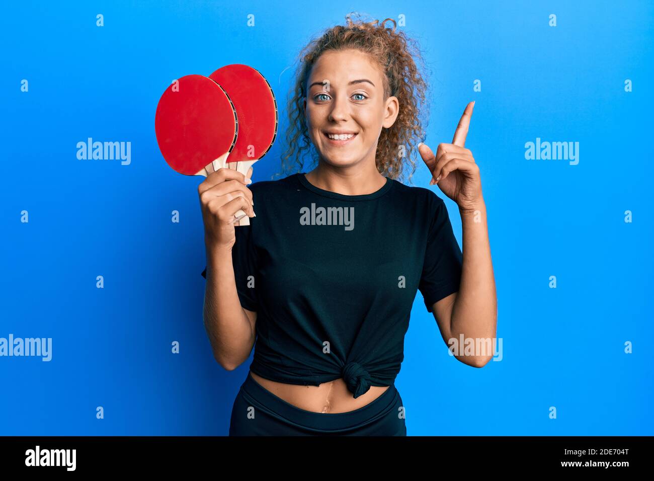 Beautiful caucasian teenager girl holding red ping pong rackets ...