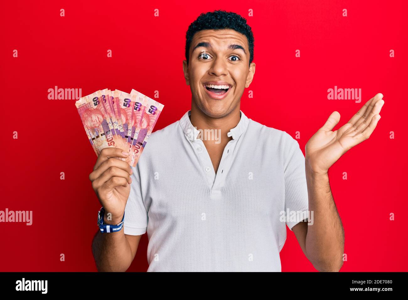 Young arab man holding south african rand banknotes celebrating ...