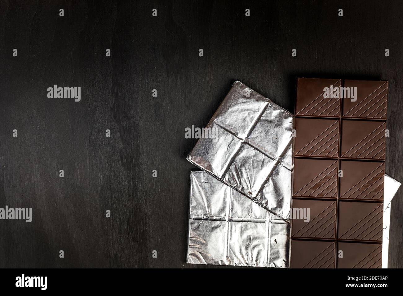 Chocolate ba on black wooden background top view. Chocolate wrapped in ...
