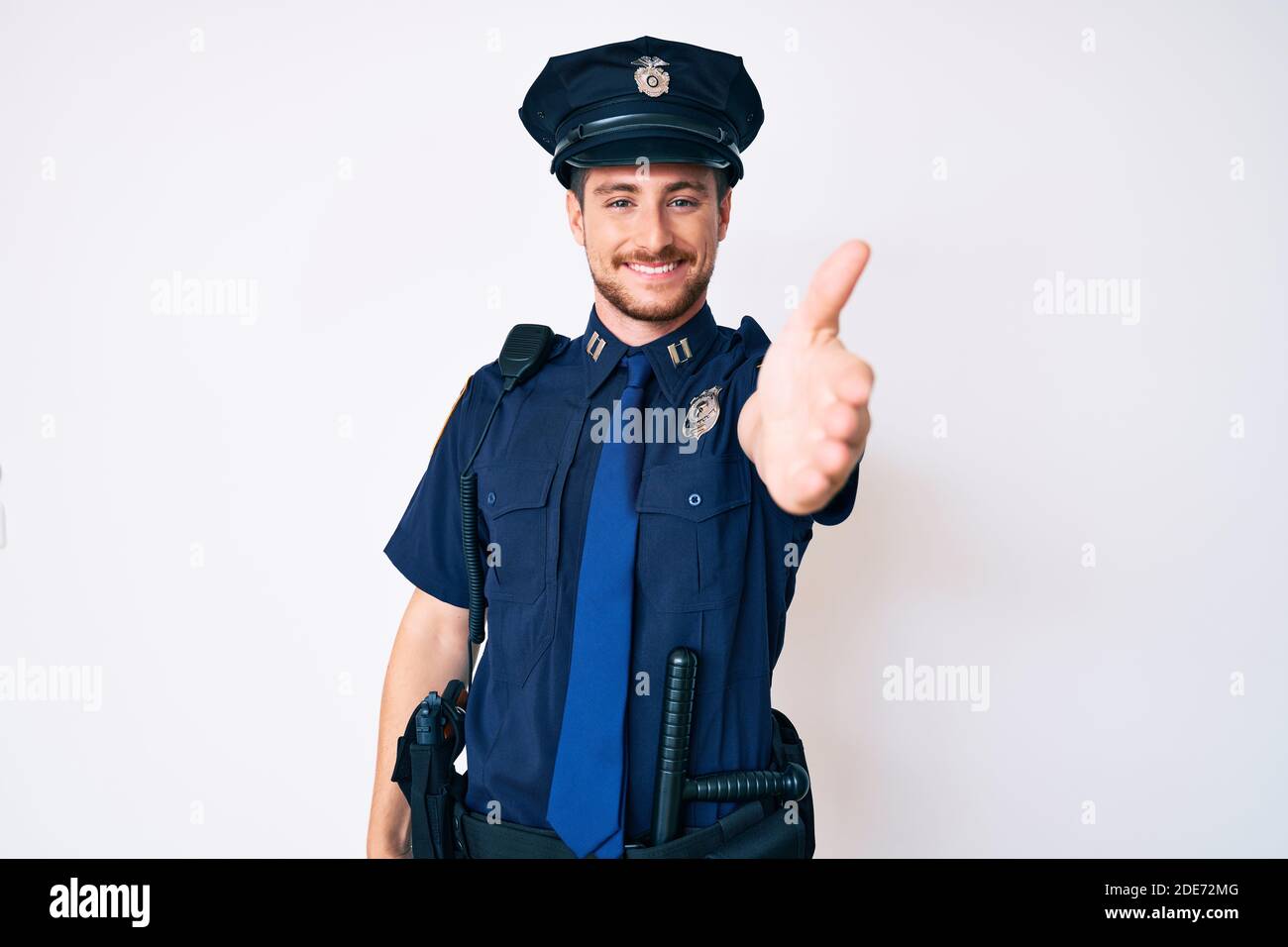 Young caucasian man wearing police uniform smiling friendly offering ...