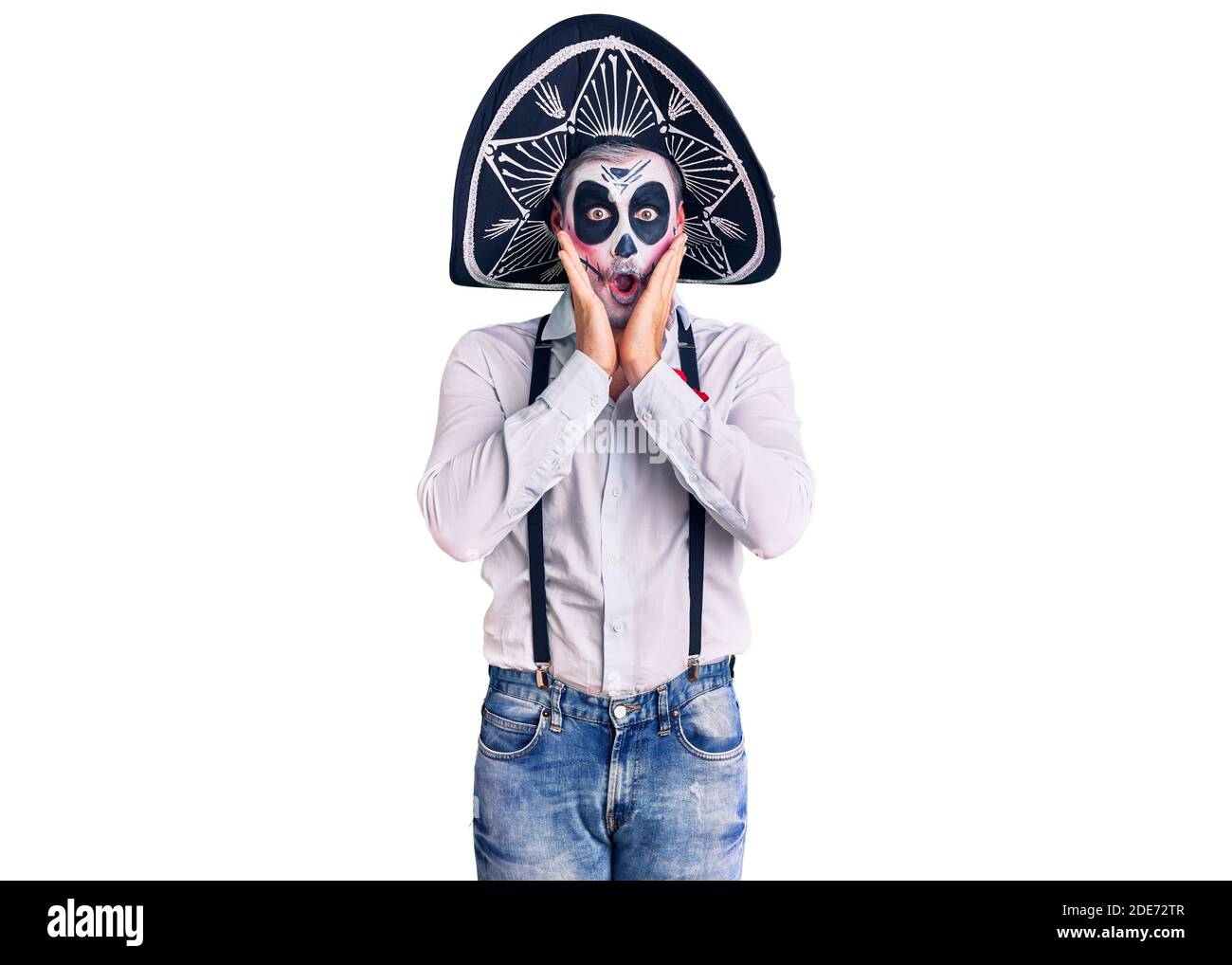 Man wearing day of the dead costume over background afraid and shocked ...