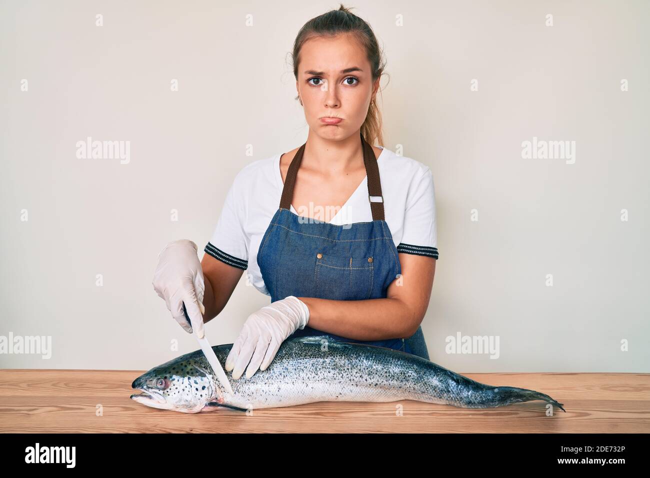 Beautiful caucasian woman fishmonger selling fresh raw salmon depressed ...