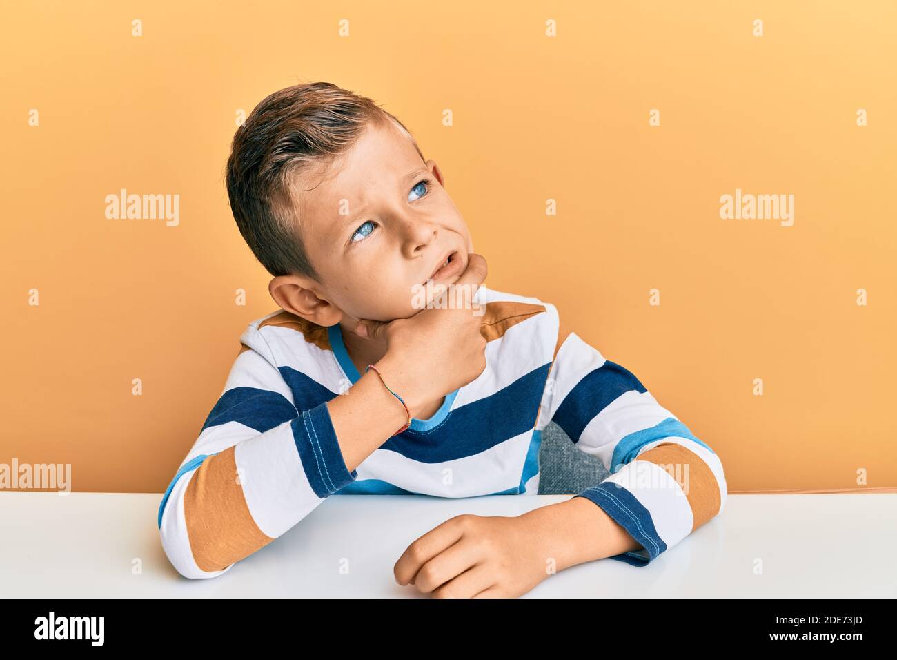 Adorable caucasian kid wearing casual clothes sitting on the table ...