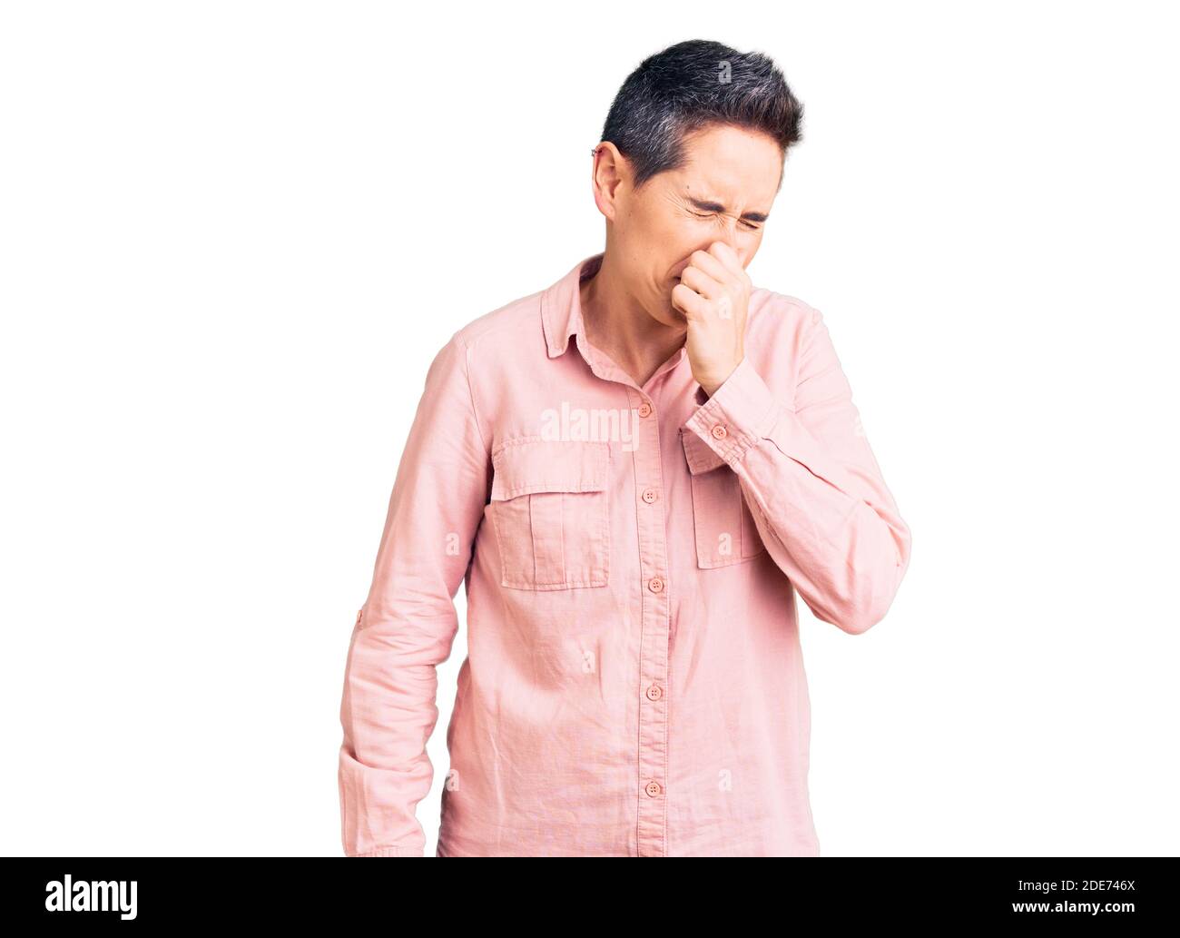 Young woman with short hair wearing casual clothes smelling something ...