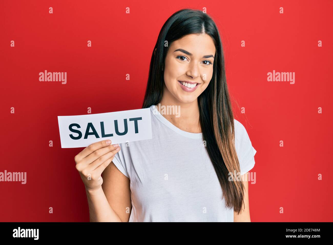 Young brunette woman holding salut french greeting looking positive and ...
