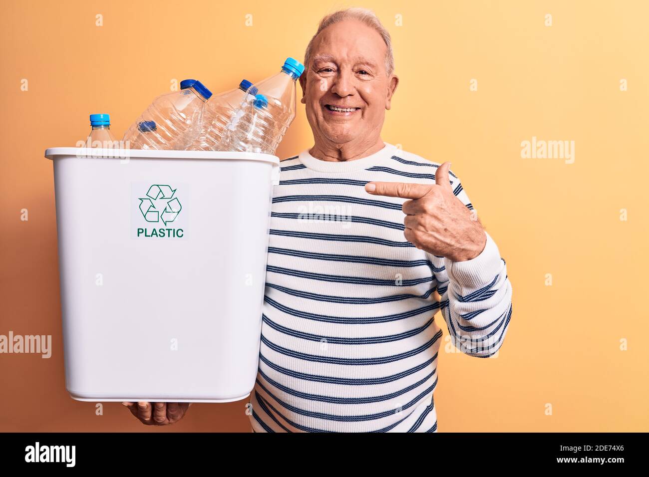 Senior handsome grey-haired man recycling holding wastebasket full of ...
