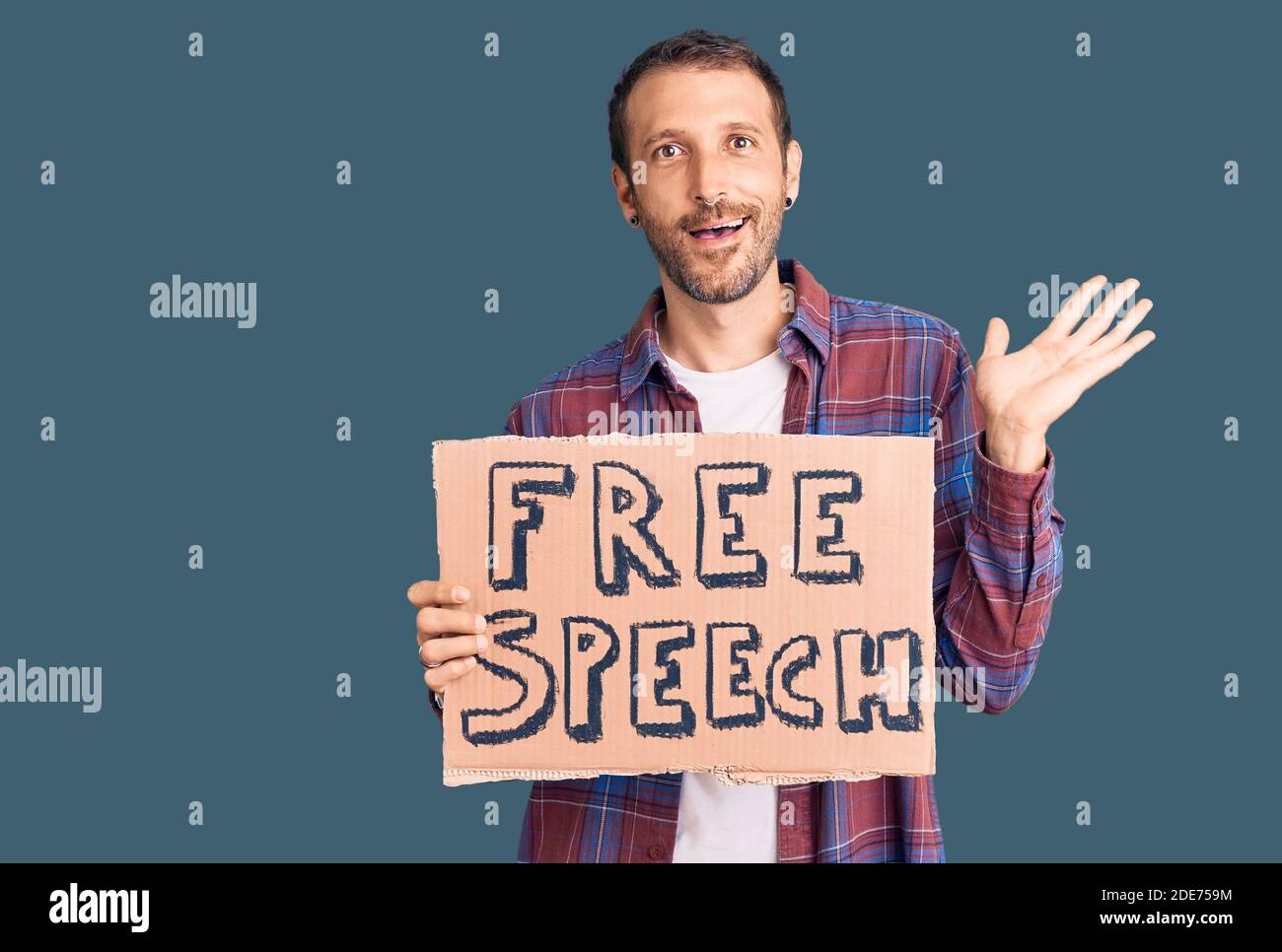Young handsome man holding free speech banner celebrating victory with ...