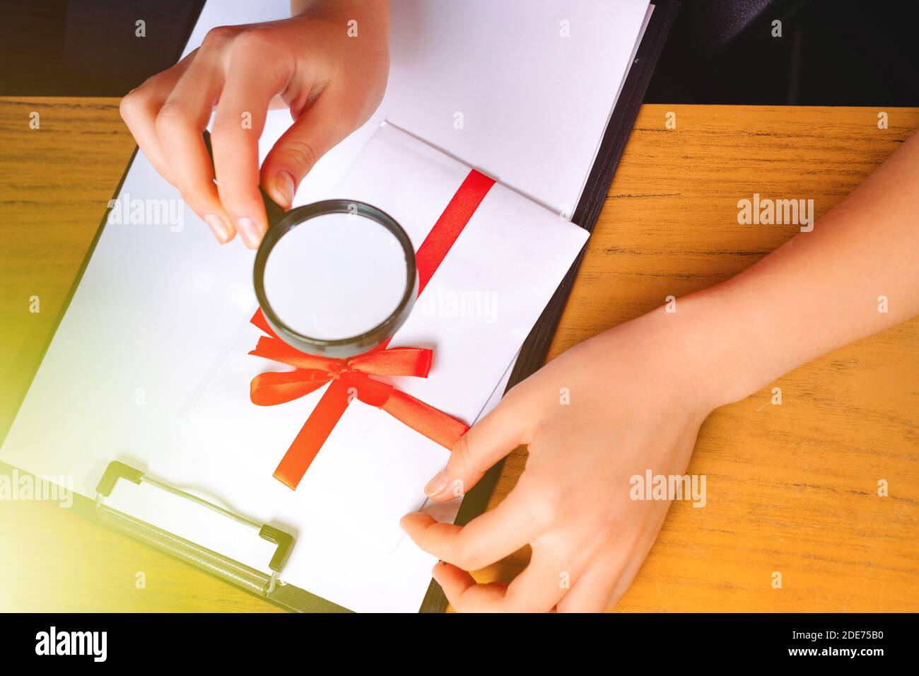 Hands holding a magnifying glass over a holiday letter and a magazine ...