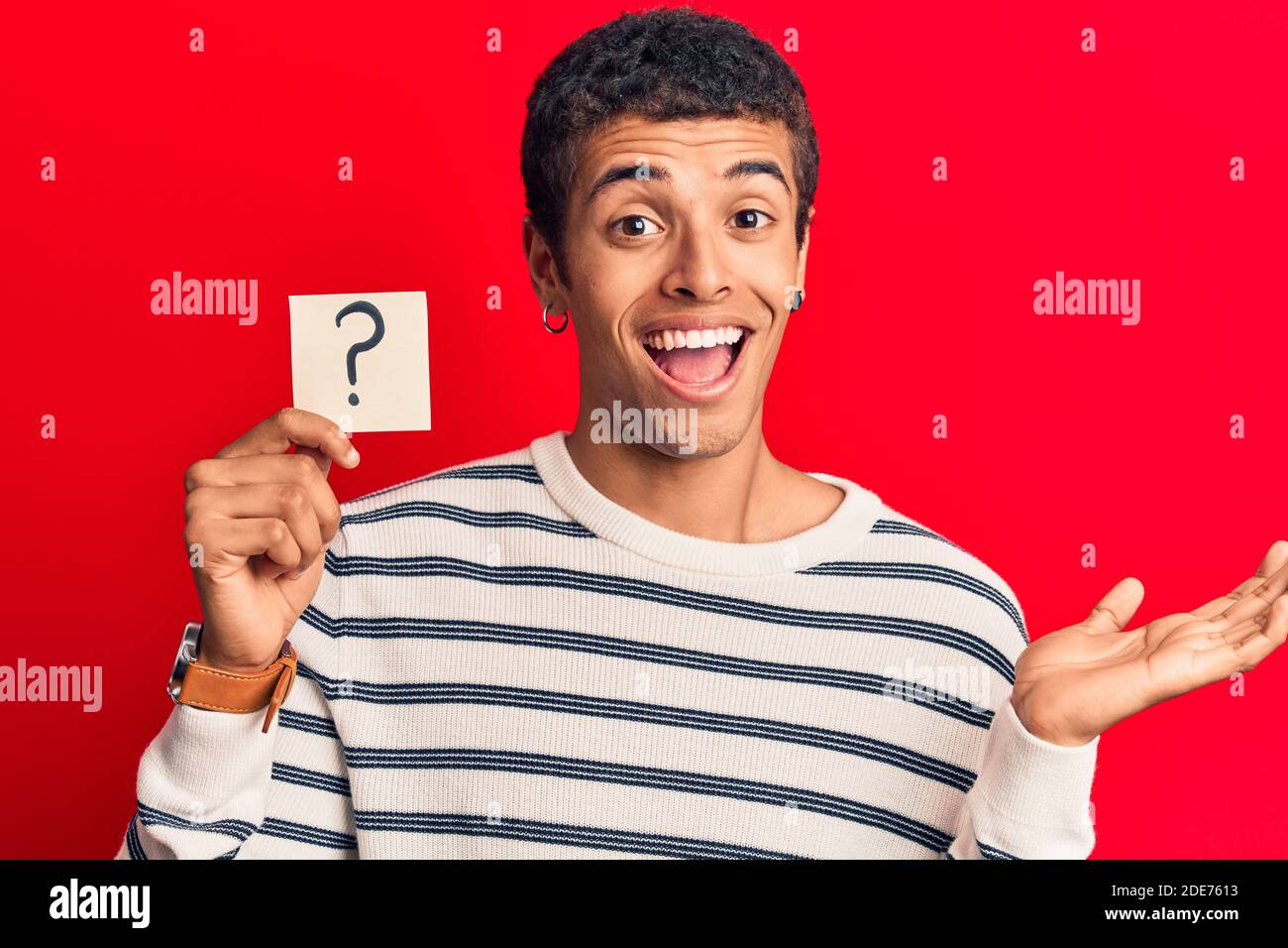 Young african amercian man holding question mark reminder celebrating ...