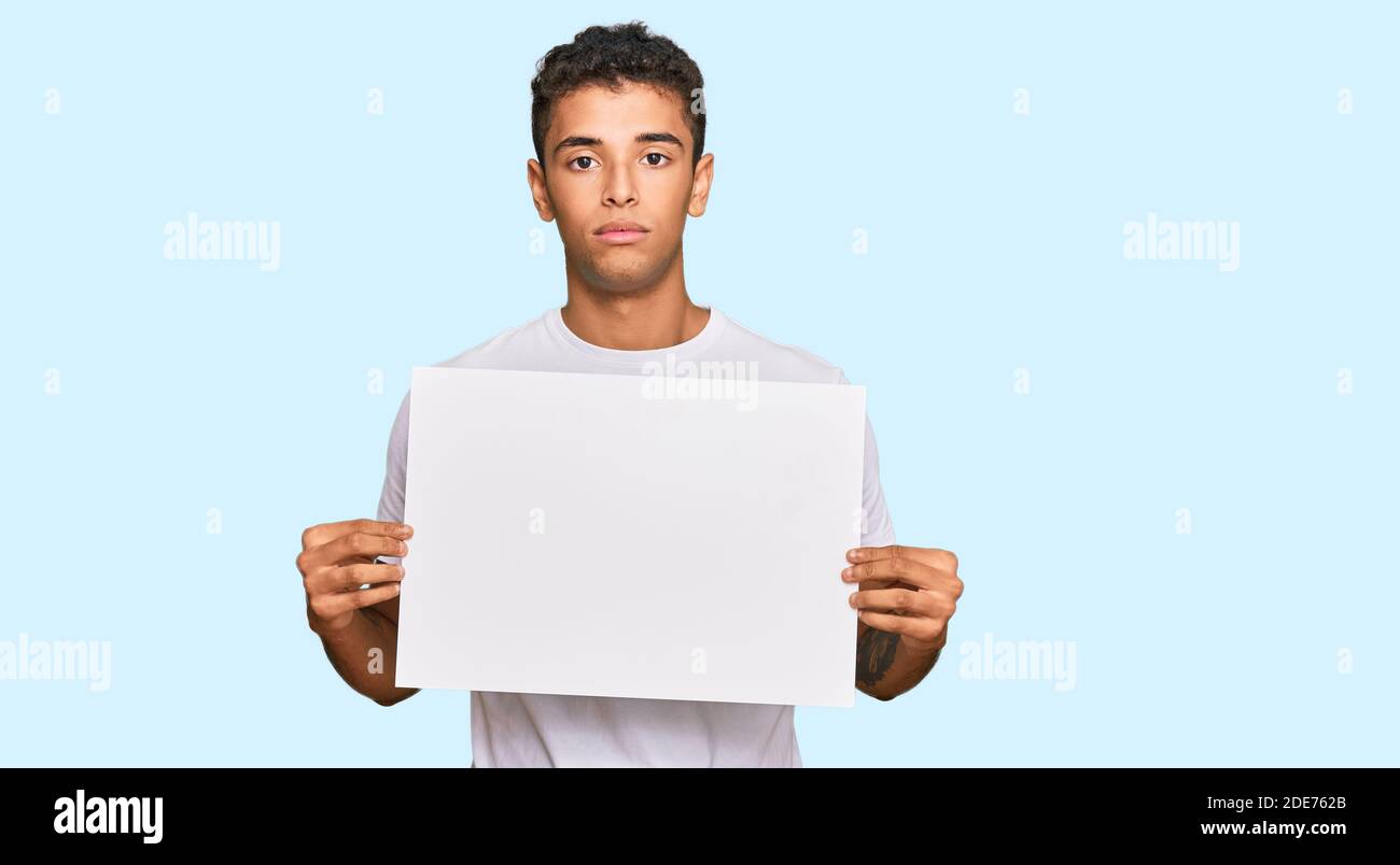 Young handsome african american man holding blank empty banner thinking ...
