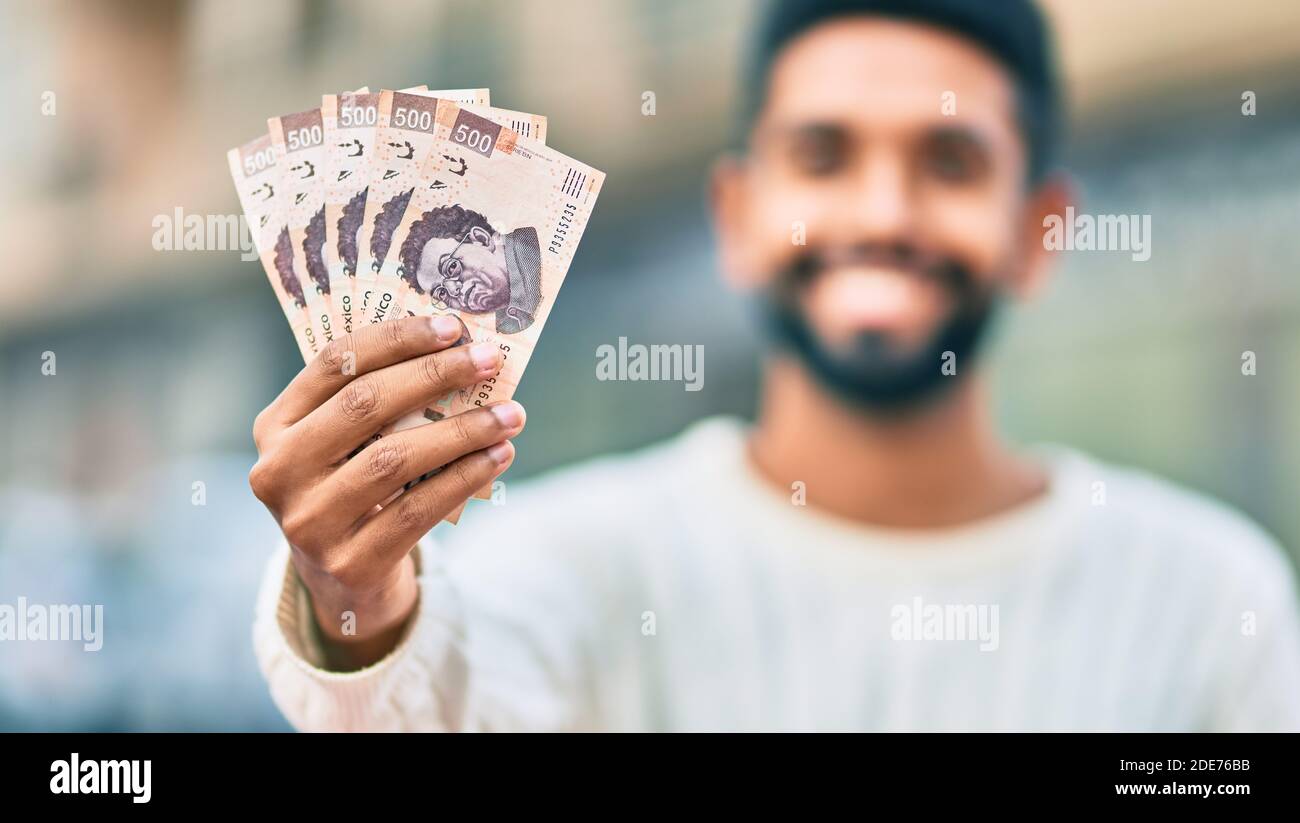 Young african american man smiling happy holding mexican 500 pesos ...