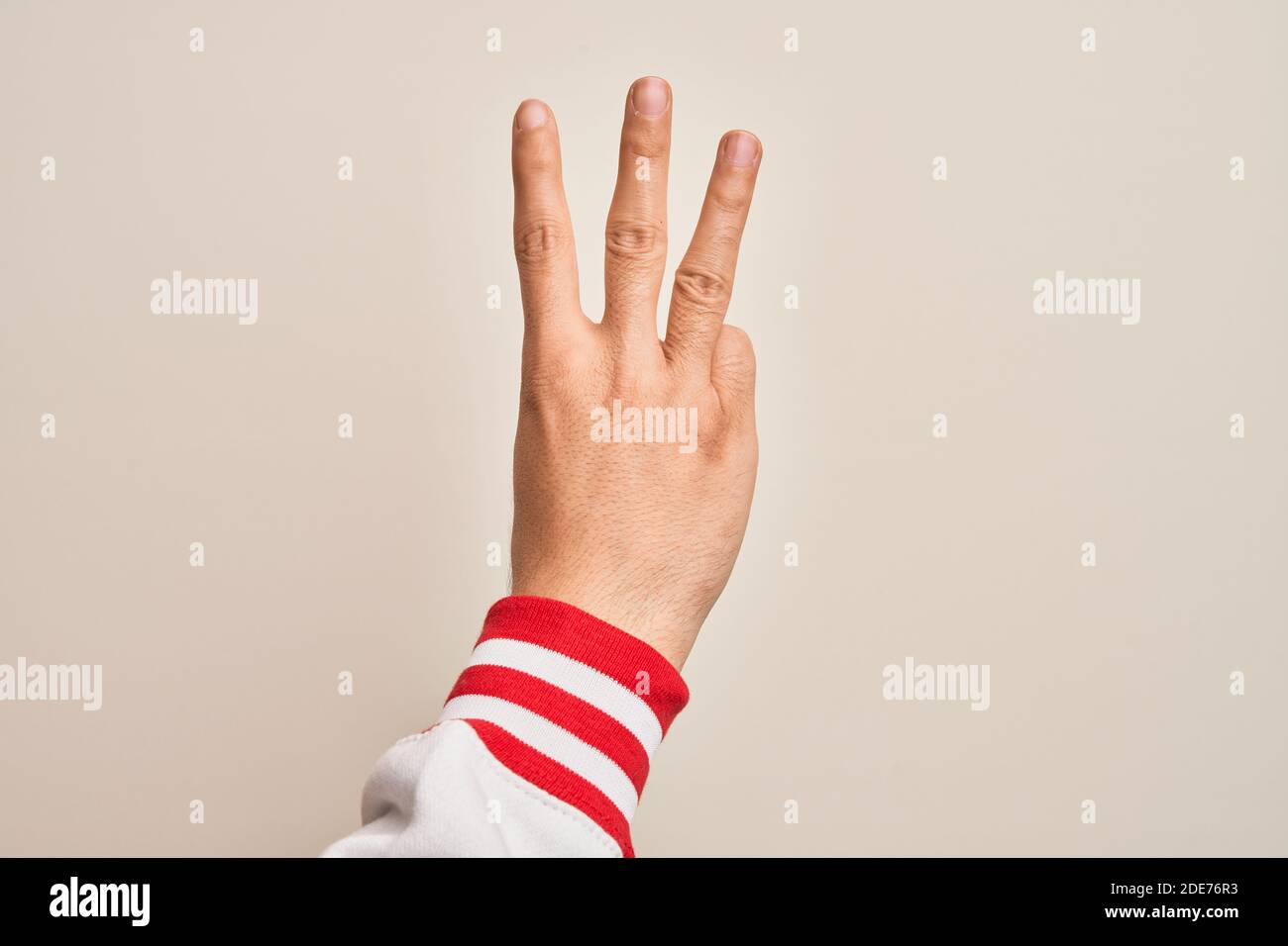 Hand of caucasian young man showing fingers over isolated white background counting number 3 ...
