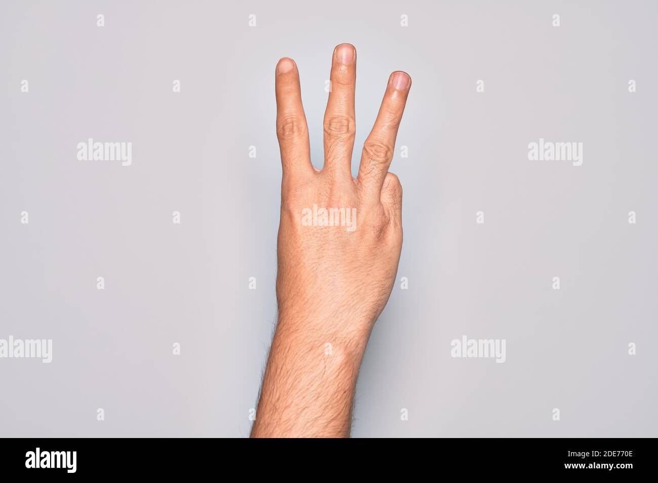 Hand of caucasian young man showing fingers over isolated white background counting number 3 ...