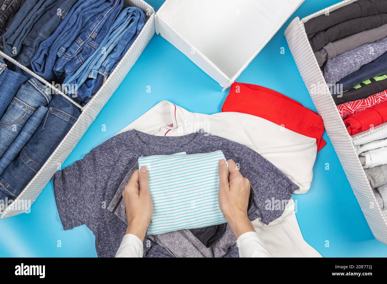 Woman hands folds and puts clothes to baskets. Vertical storage of ...