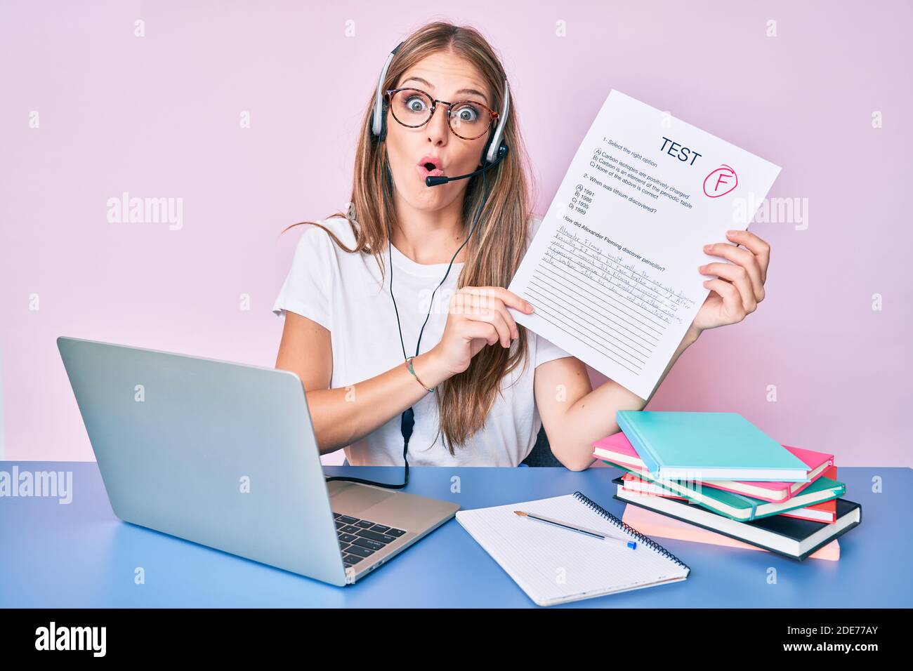 Young blonde girl showing failed exam sitting on the table scared and ...