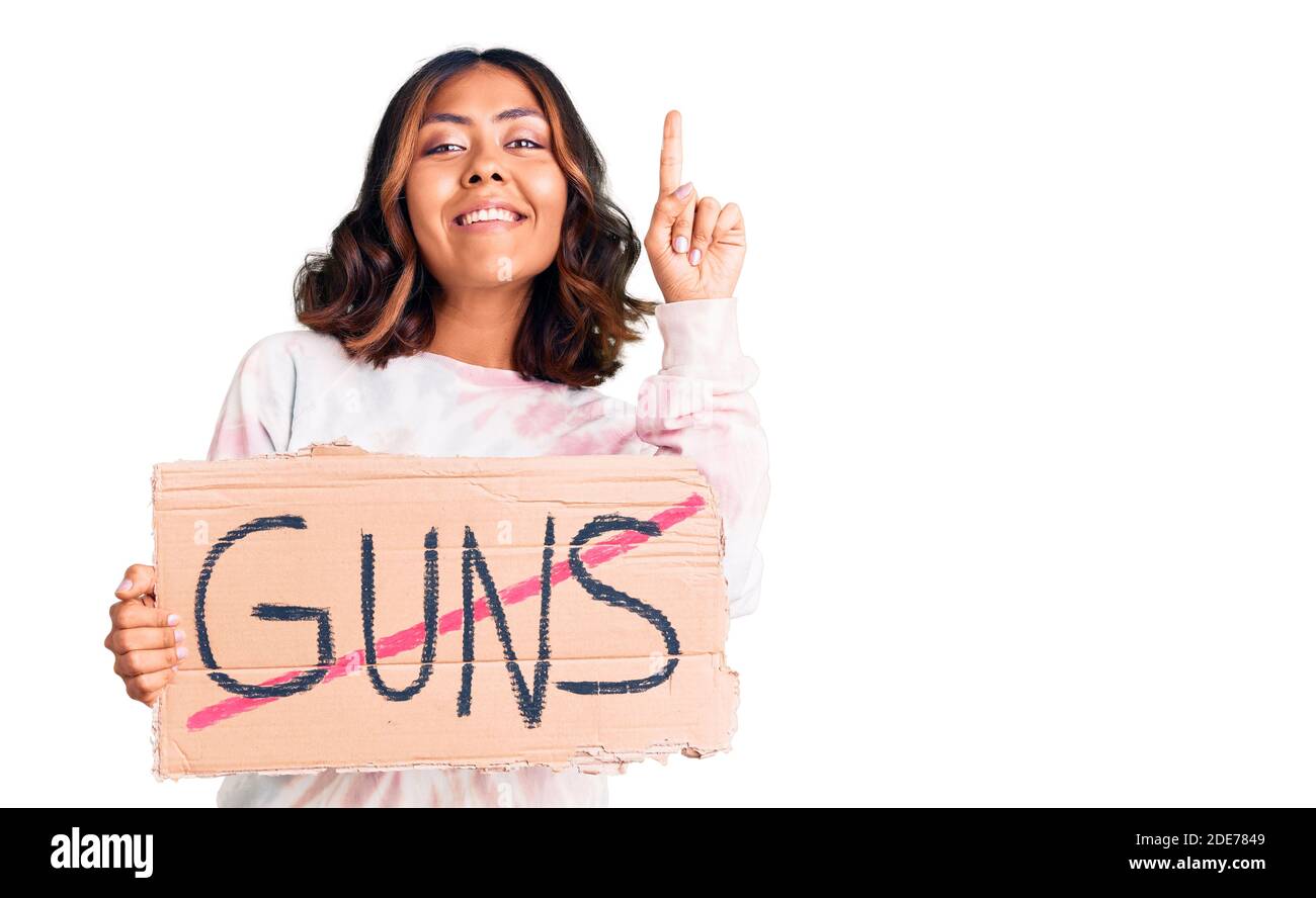 Young beautiful mixed race woman holding no guns warning banner ...