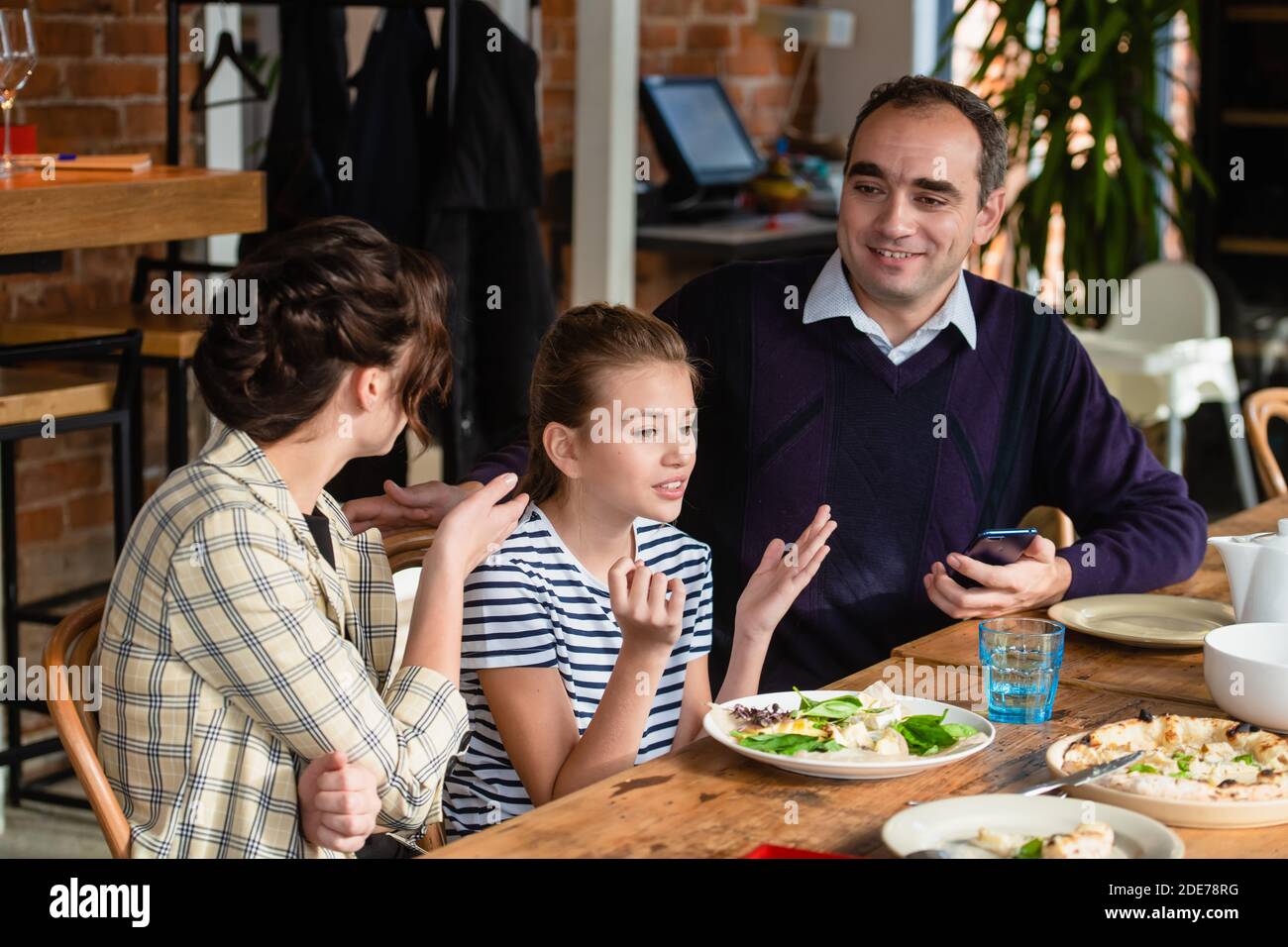 Family of three chatting at a dining table Stock Photo - Alamy