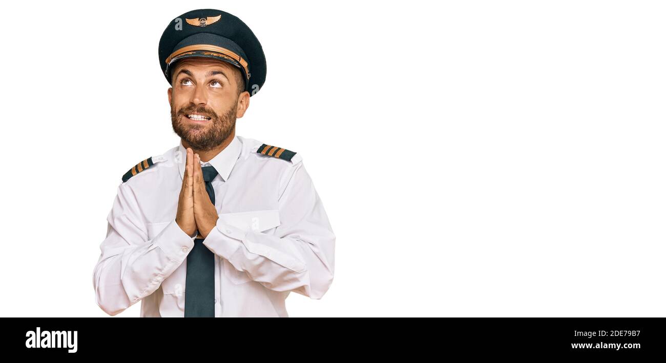 Handsome man with beard wearing airplane pilot uniform begging and ...