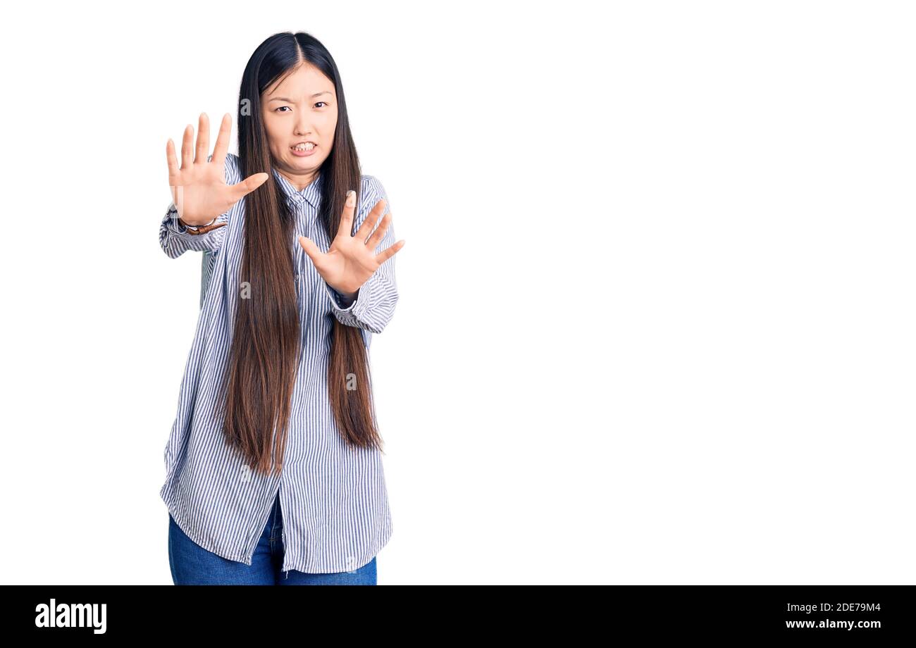 Young beautiful chinese woman wearing casual shirt afraid and terrified ...