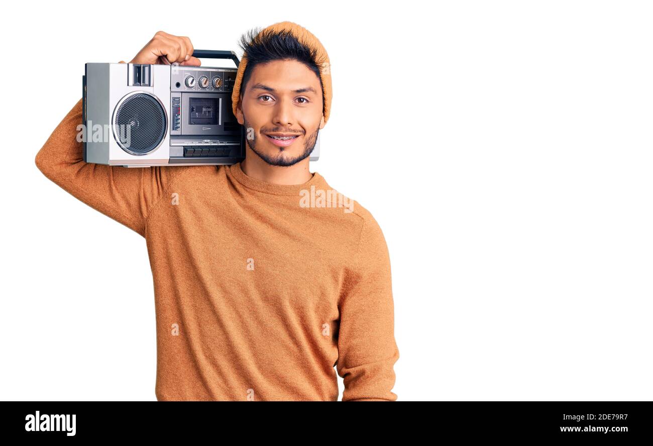 Handsome latin american young man holding boombox, listening to music ...
