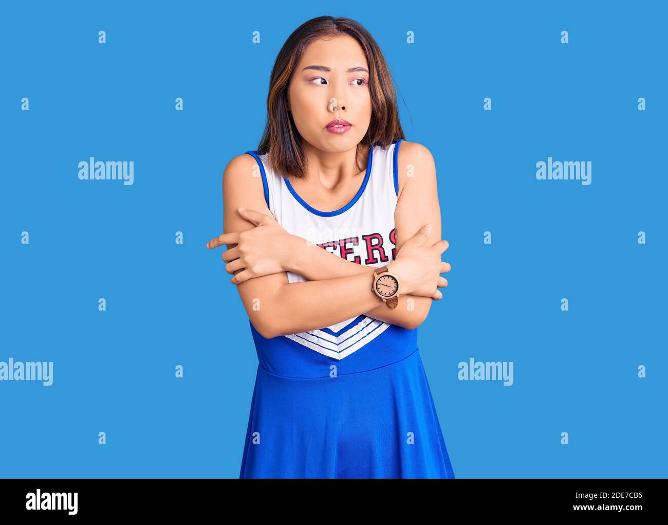 Young beautiful chinese girl wearing cheerleader uniform shaking and ...
