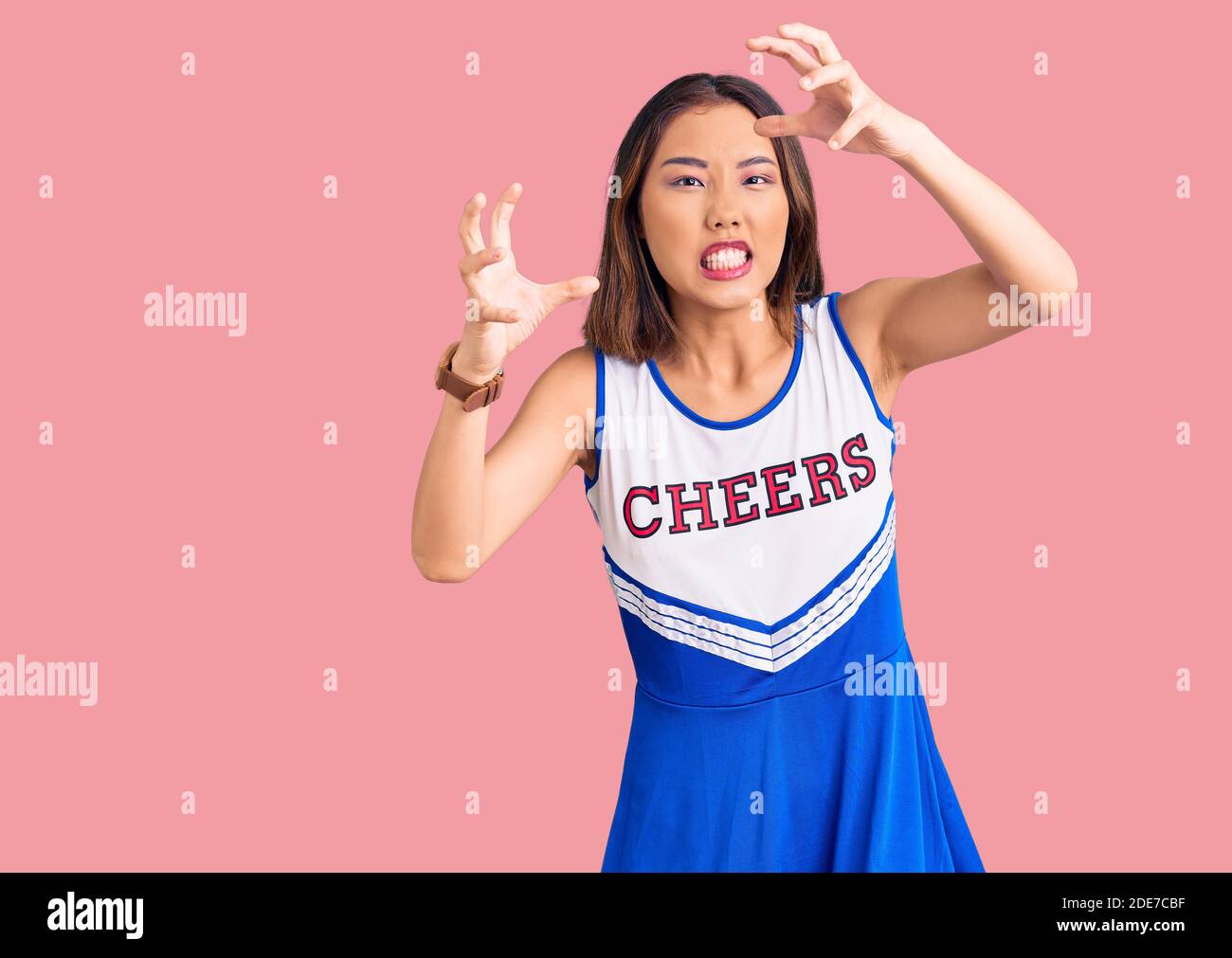 Young beautiful chinese girl wearing cheerleader uniform shouting ...