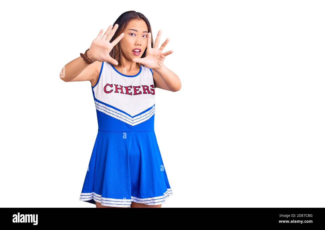 Young beautiful chinese girl wearing cheerleader uniform afraid and ...