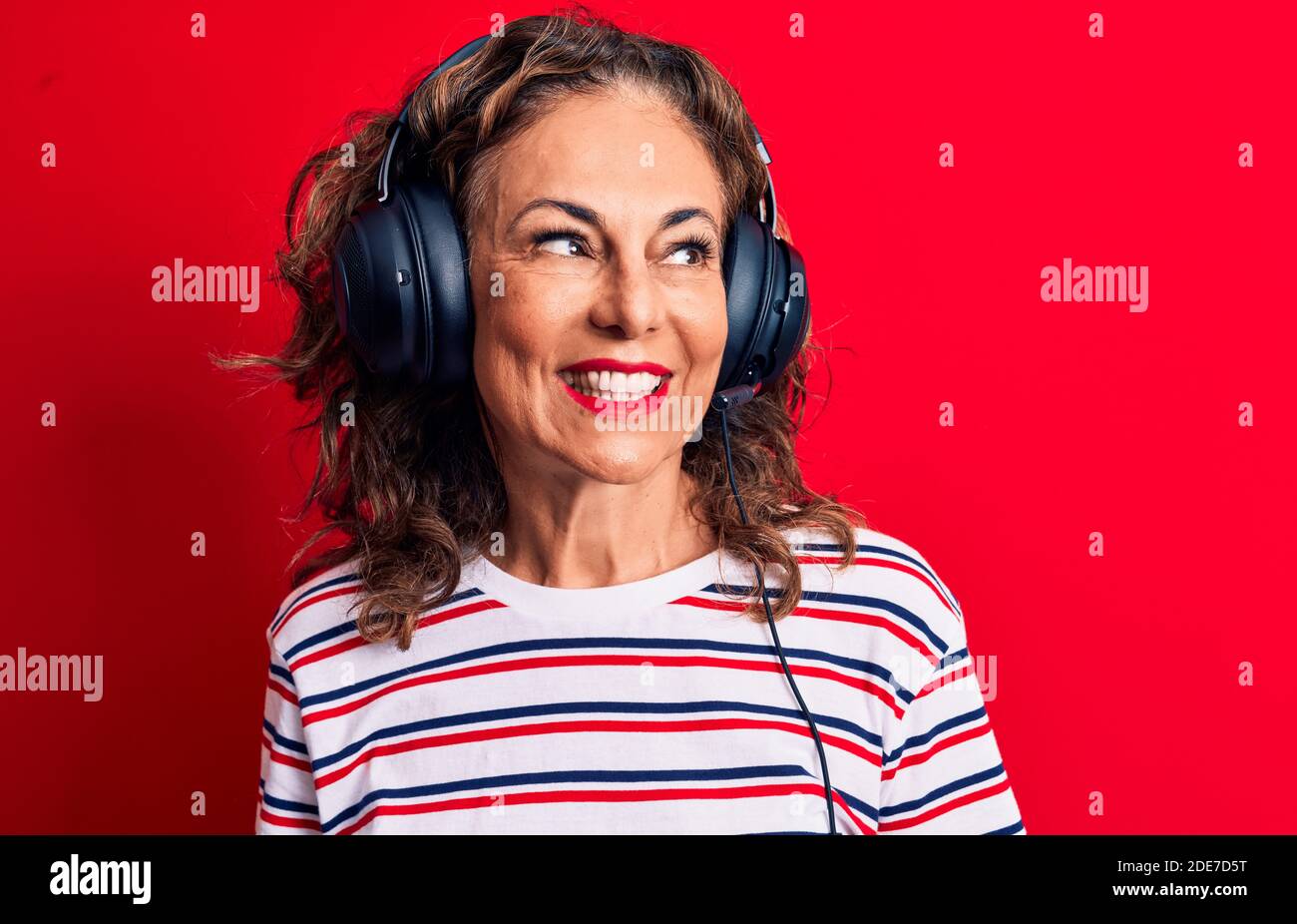 Middle age brunette gamer woman playing video game using headphones and ...