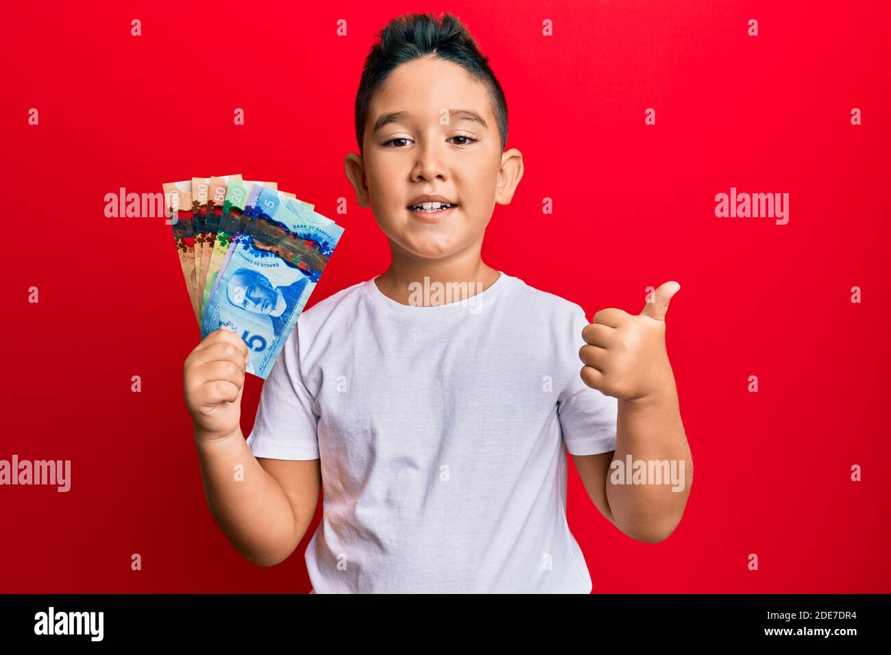 Little boy hispanic kid holding canadian dollars smiling happy and ...