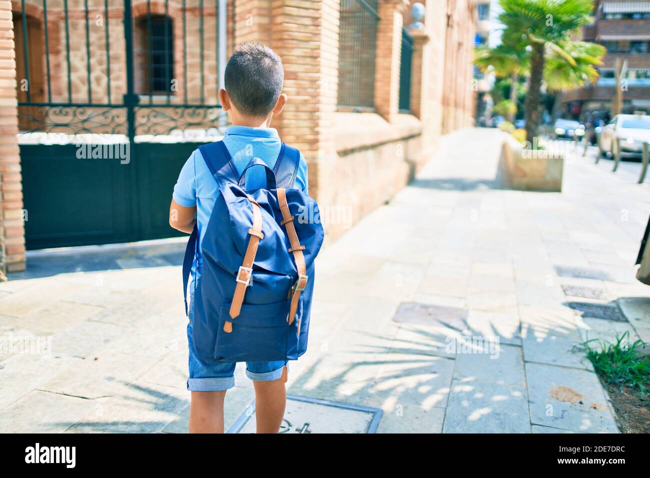 Adorable student boy on back view wearing backpack at street of city ...
