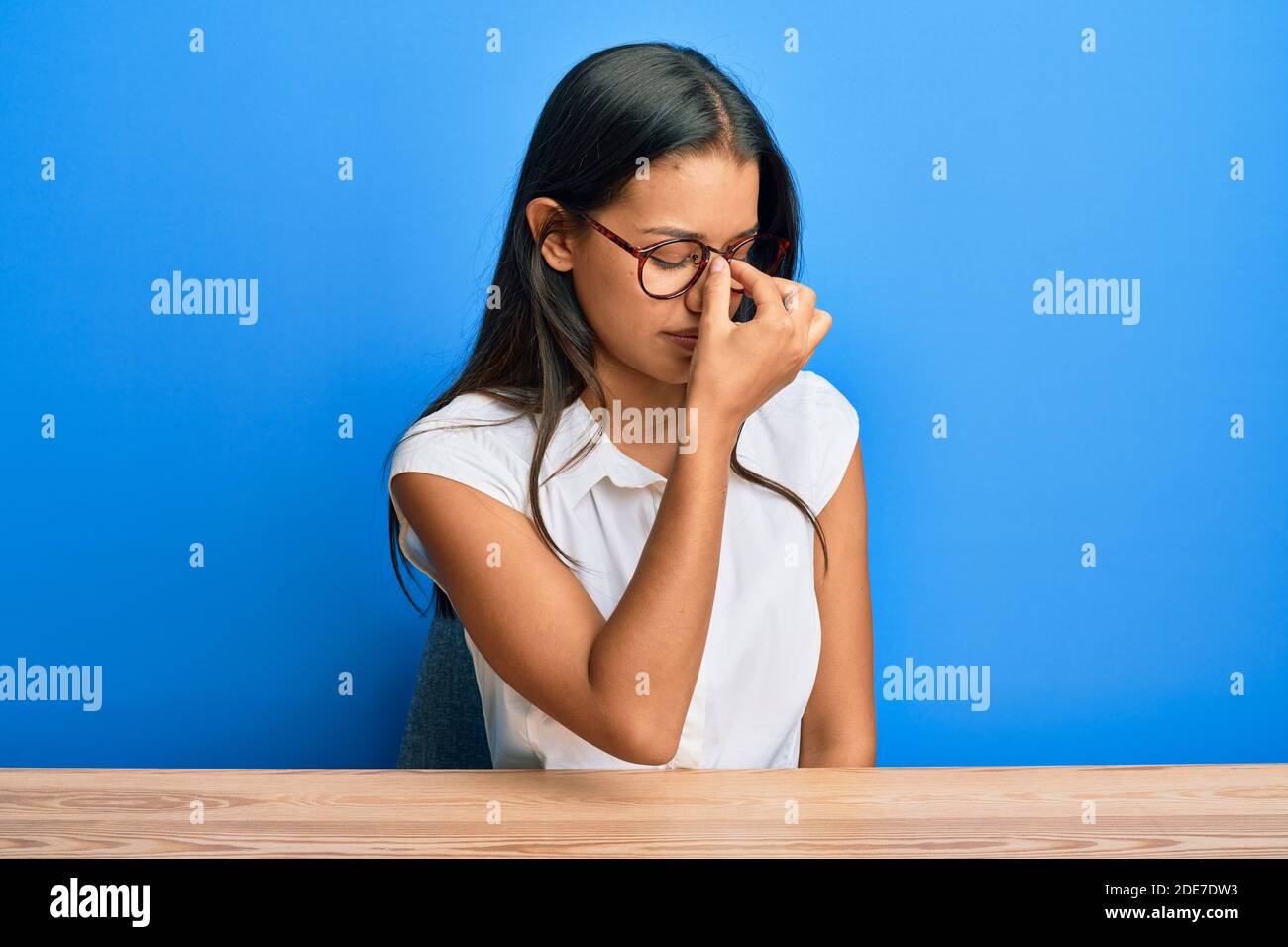 Beautiful hispanic woman wearing casual clothes sitting on the table ...
